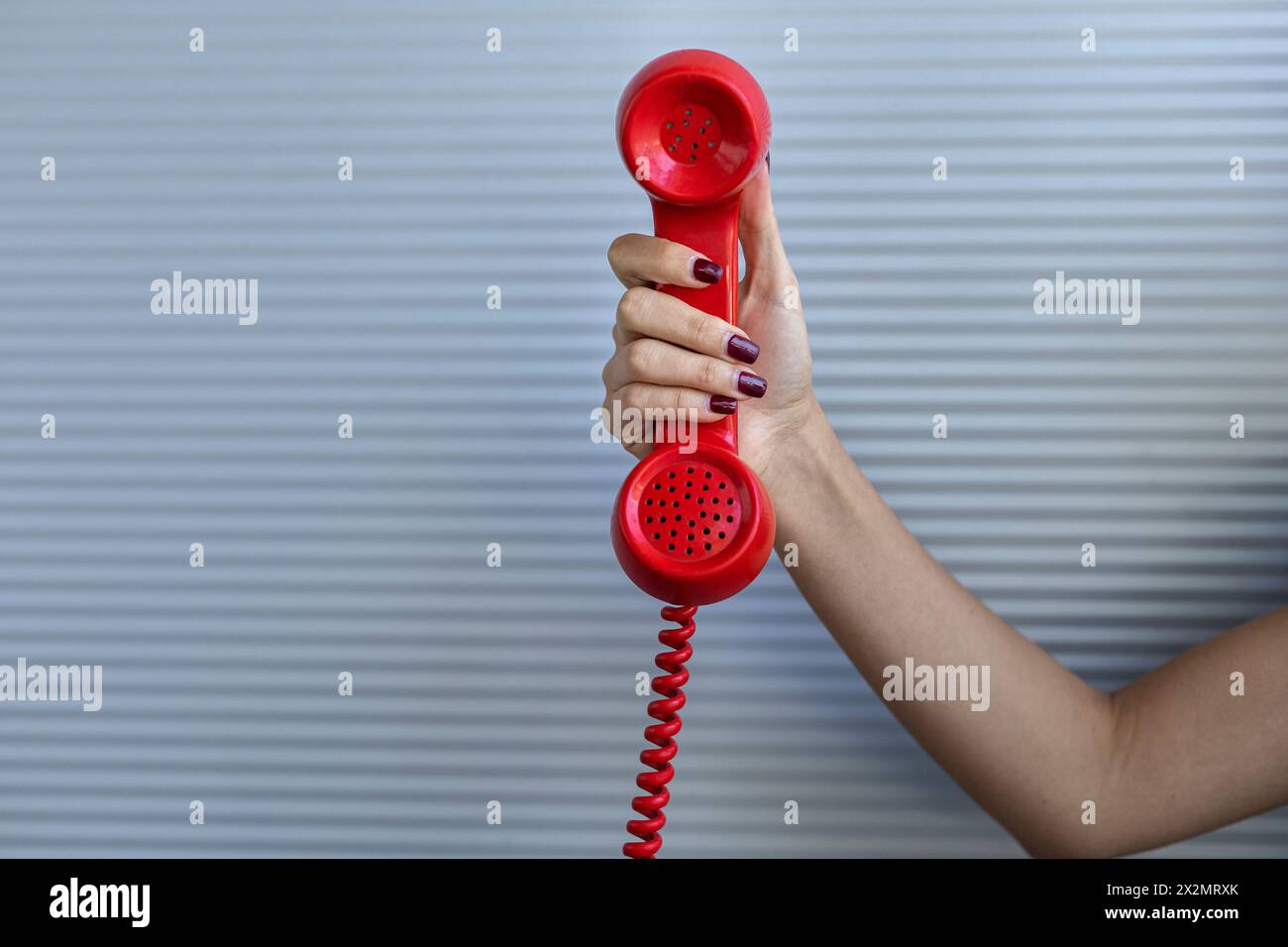Red handset held by a woman's hand. Gray background. Vintage technology ...