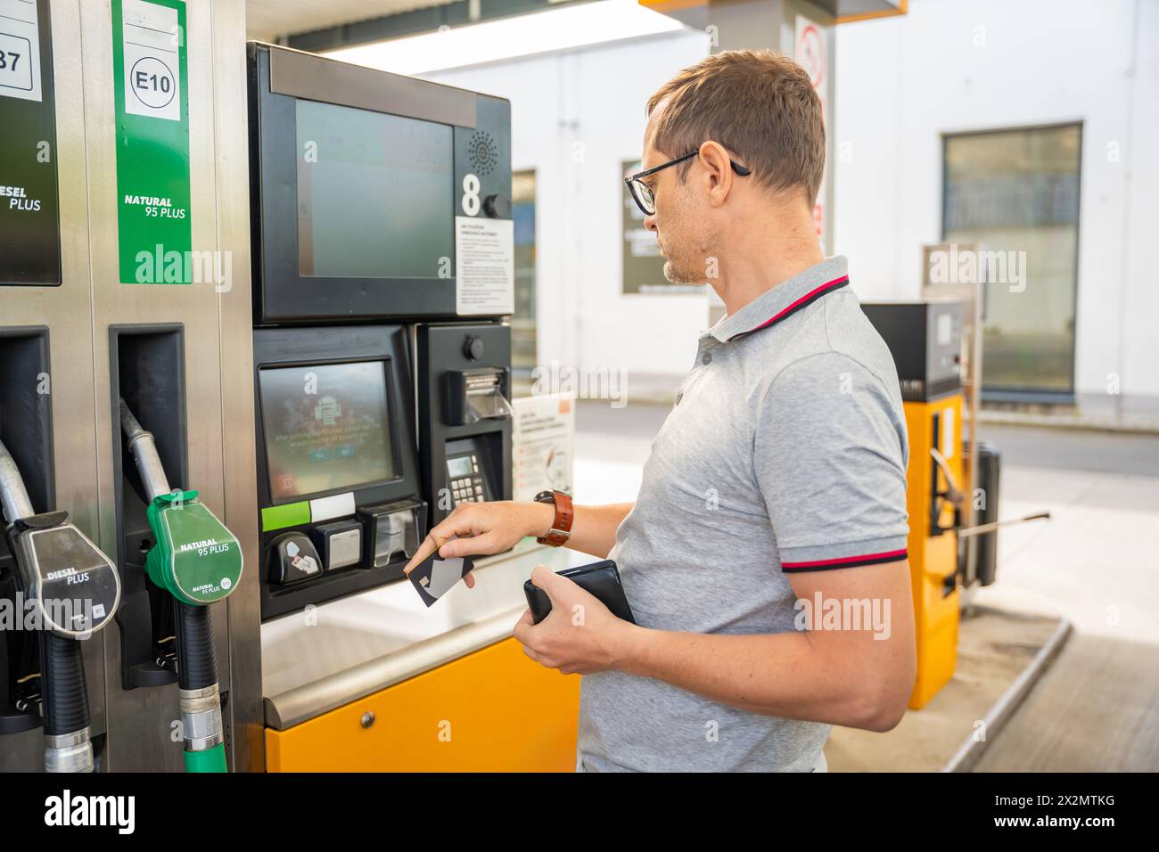 The man pays for fuel with a credit card on terminal of self-service ...