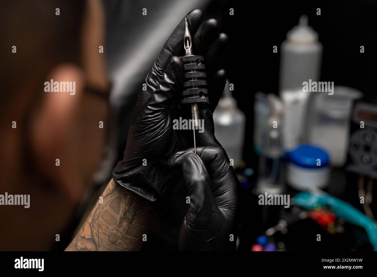 Tattooist assembling the sterilized needle in the grip. Wearing black ...