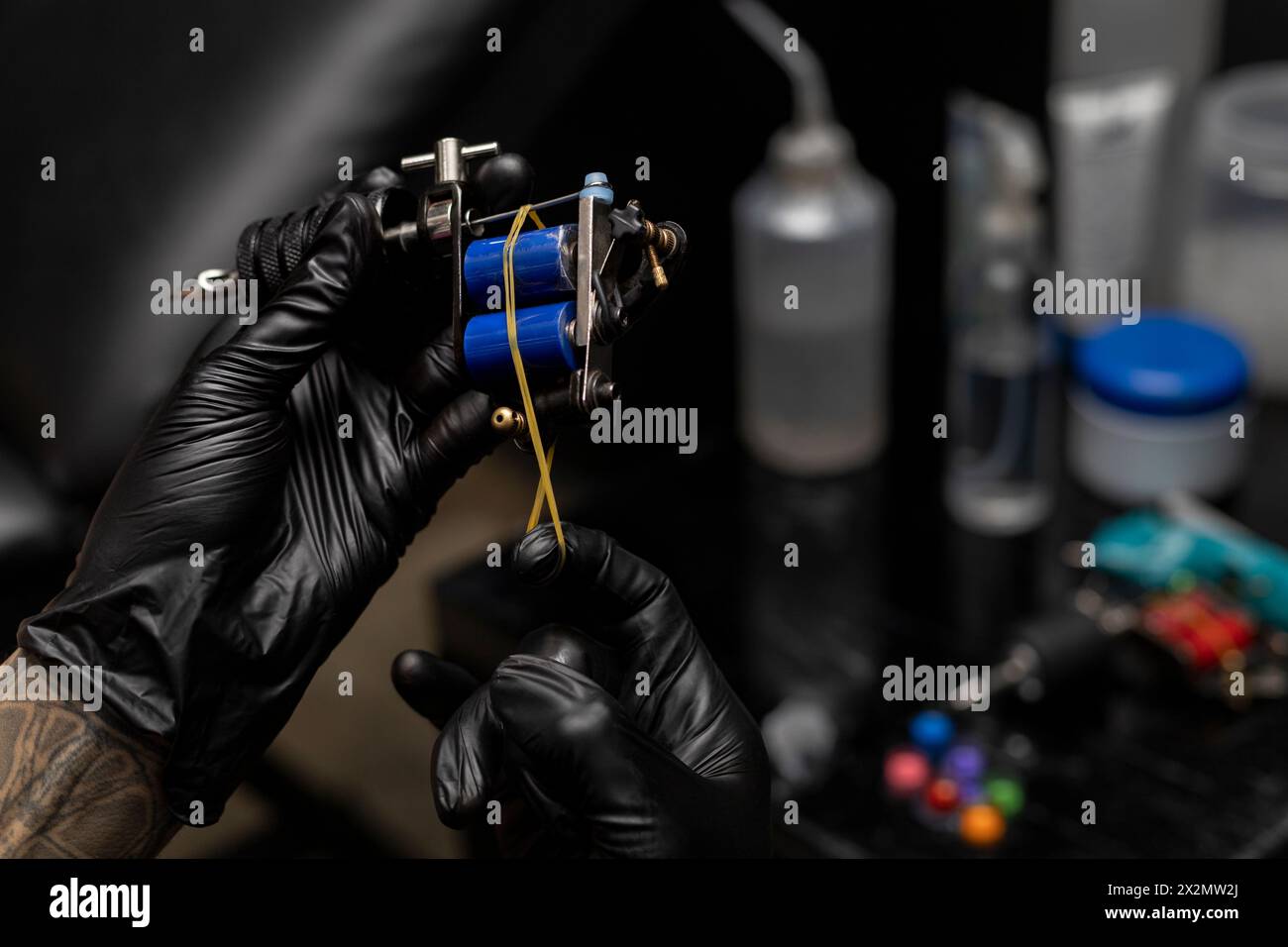 Tattooist setting up and adjusting his tattoo machine. Wearing black ...