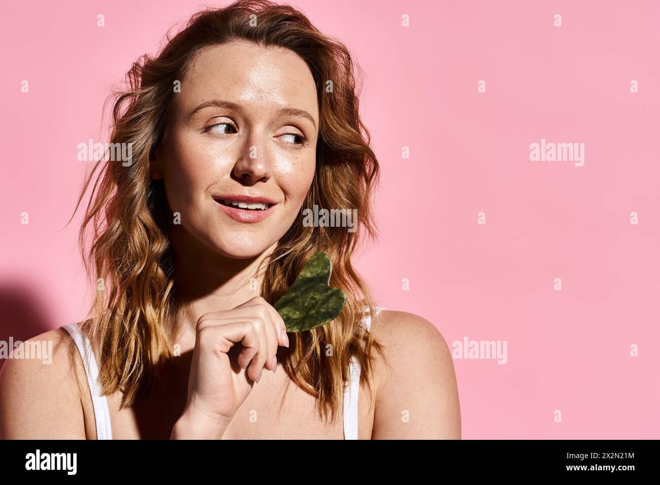 An attractive woman delicately holds gua sha, showcasing her natural ...