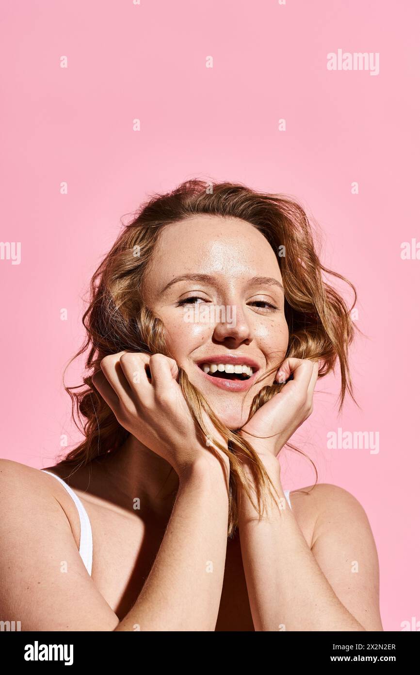 A radiant woman smiles joyfully, hands delicately framing her face in a ...