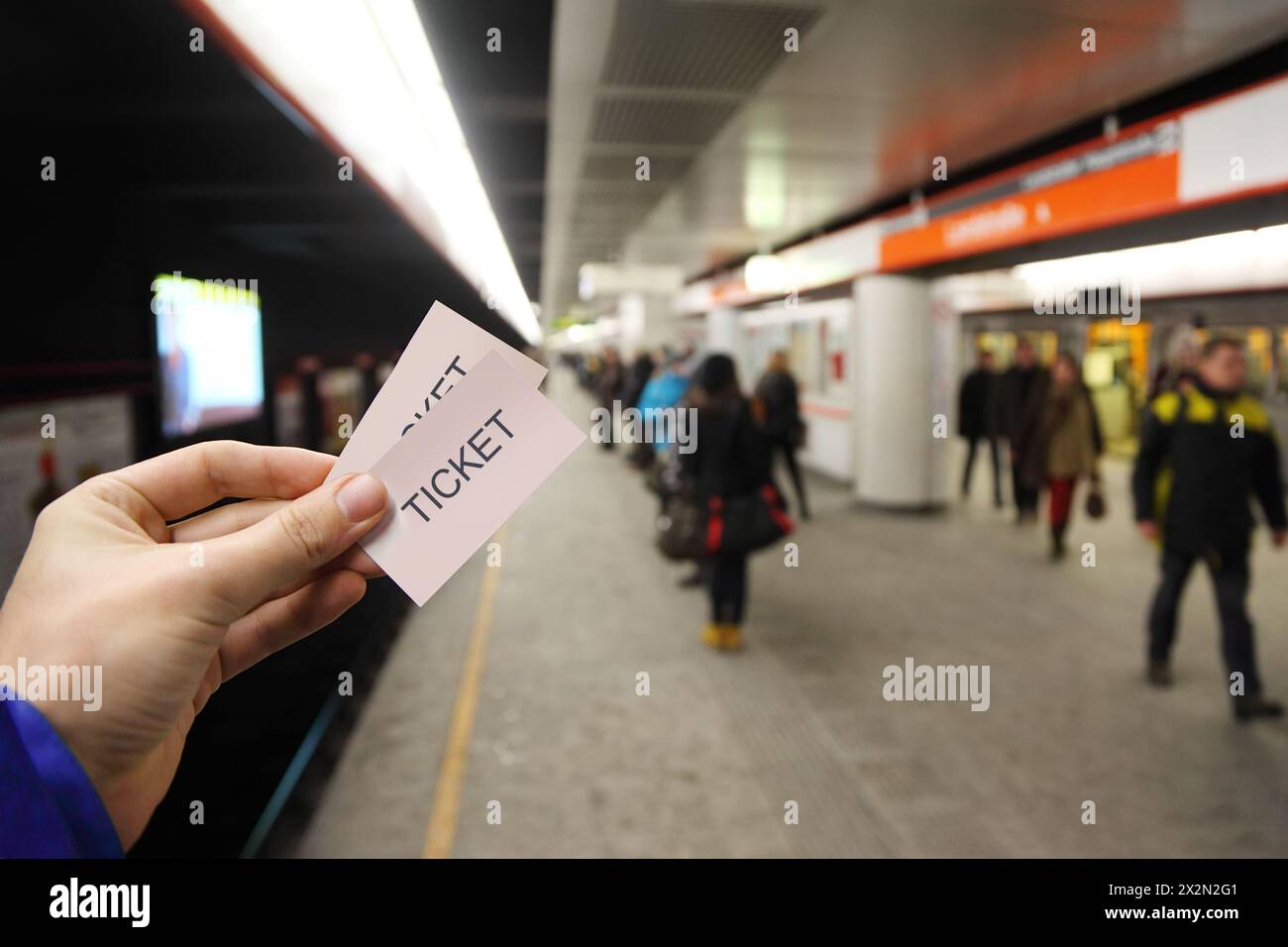 Male hand holds two tickets in subway. People wait for train on ...