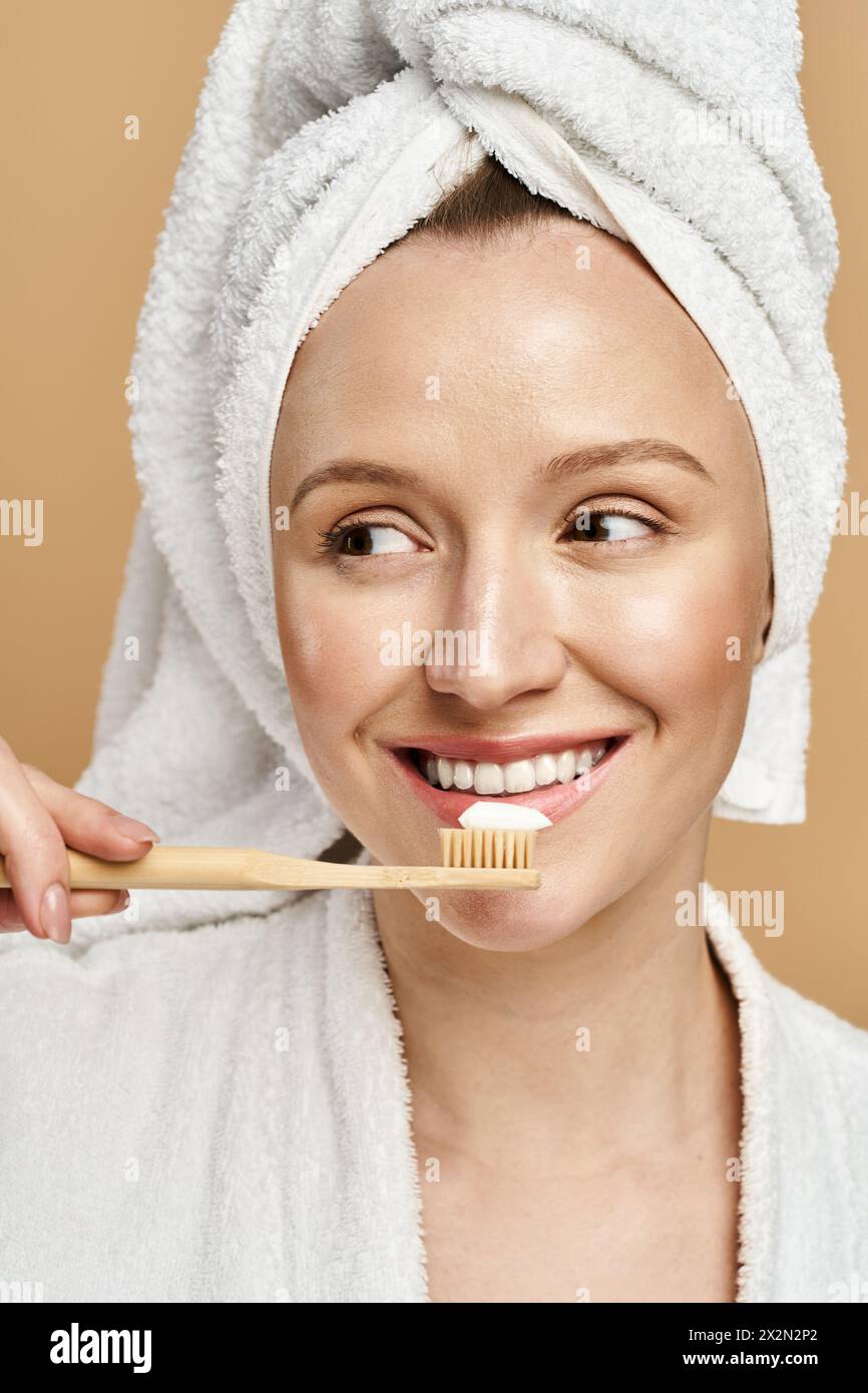 A natural beauty woman actively brushes her teeth while wearing a towel ...