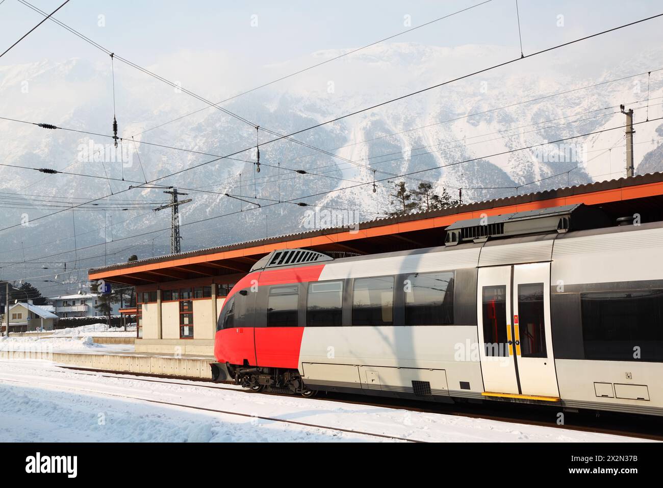 Modern train stops at station near high mountains at winter Stock Photo ...