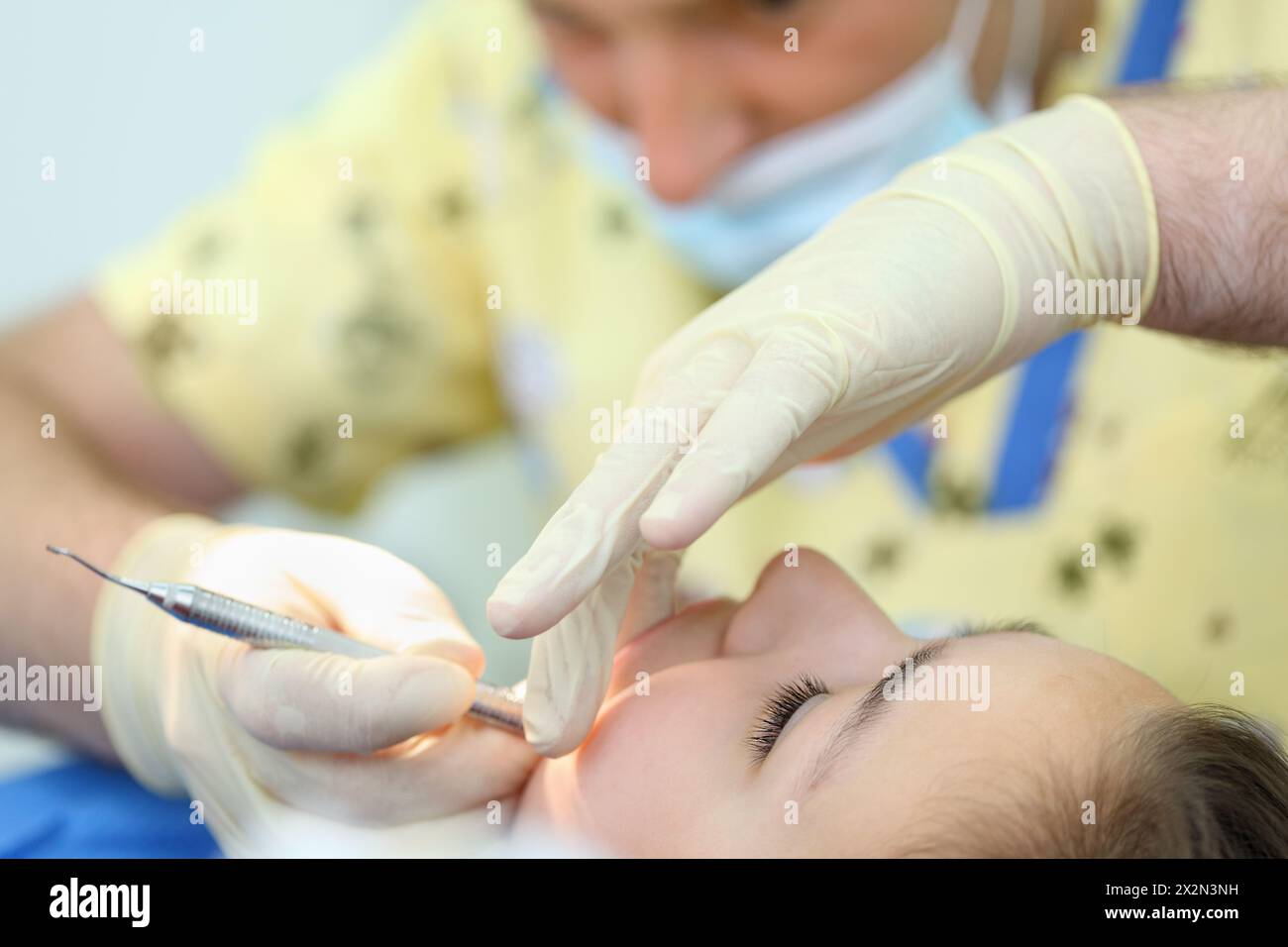 Dentist treats teeth of girl in dental clinic. Shallow depth of field ...