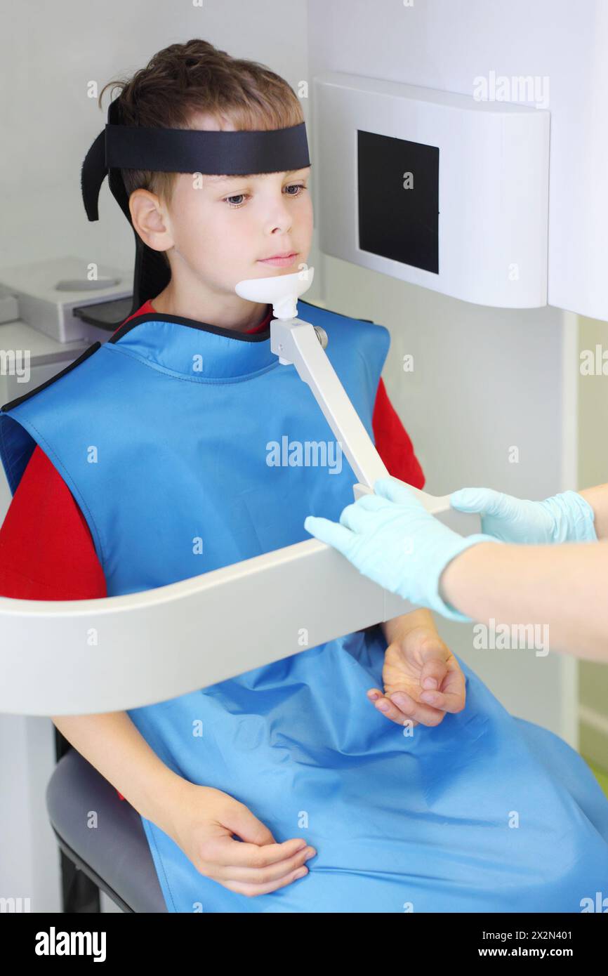 Dentist hands prepare boy wearing in protective lead apron to jaw x-ray ...