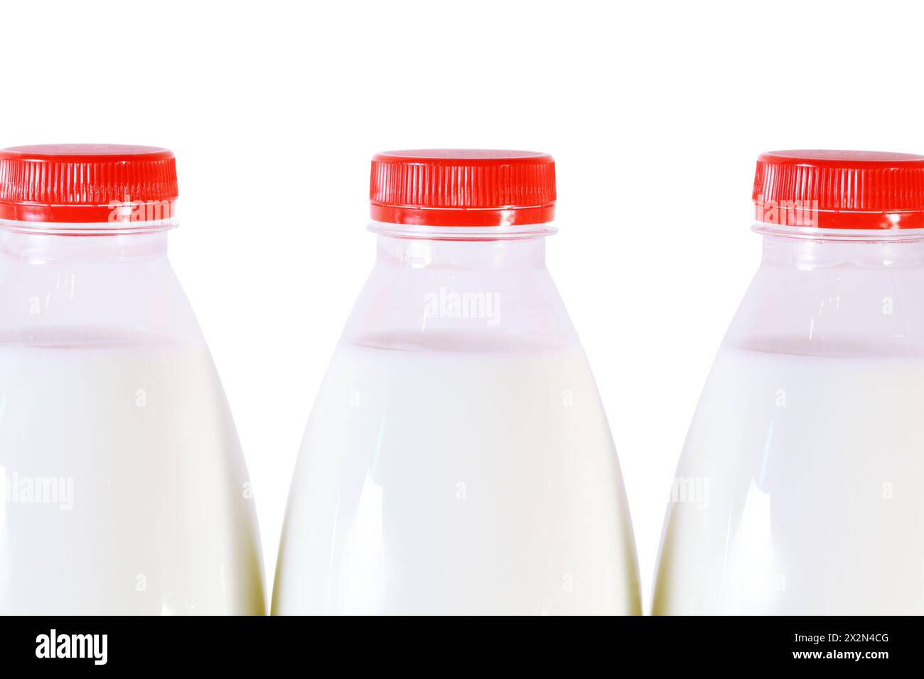 Part of three bottles of milk with red cap isolated on white background ...