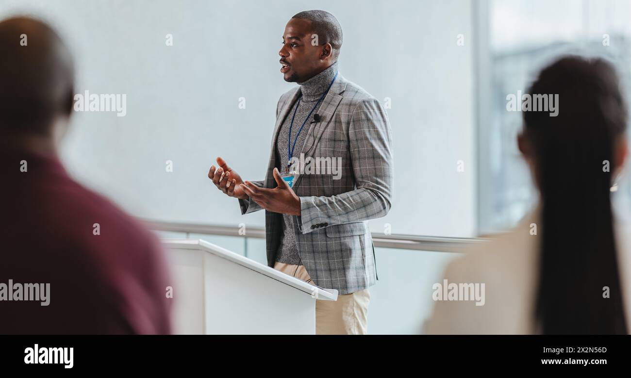 Speaker presenting at a professional seminar in a bright, modern ...