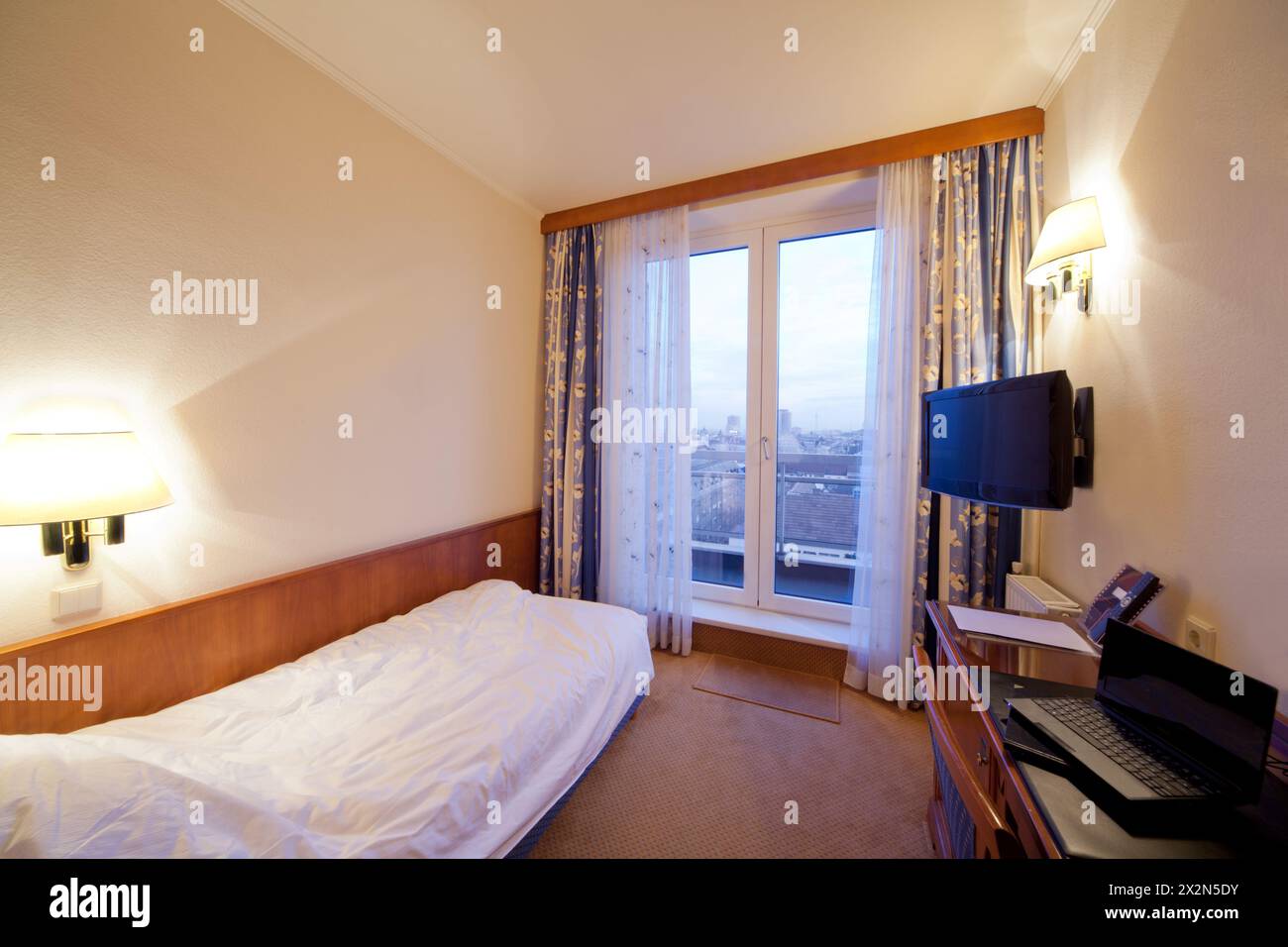 Hotel room with bed, tv, mirror, notebook, window Stock Photo - Alamy
