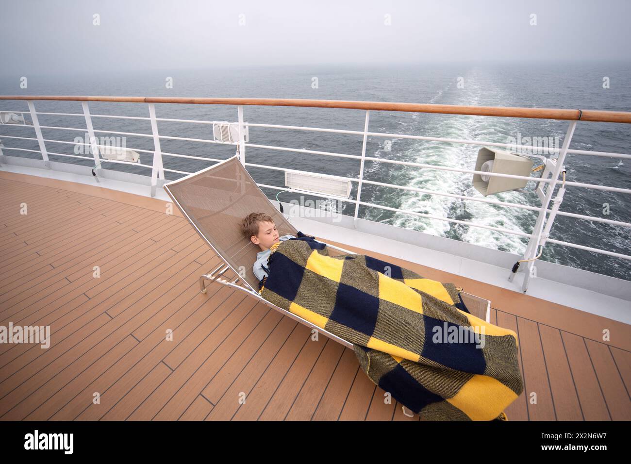 Little boy sleeping on cot covered with blanket on board large ...