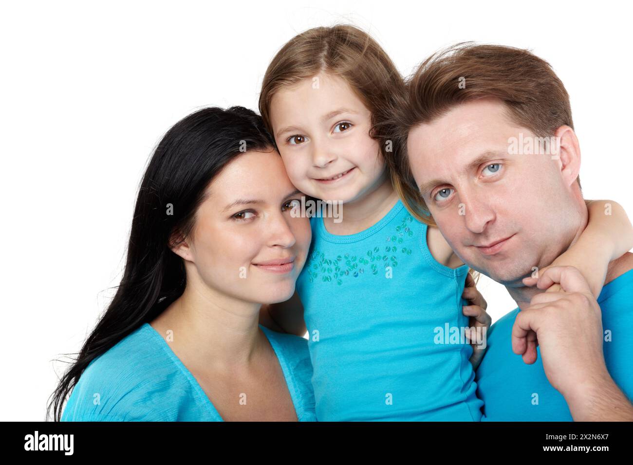 Family of three in blue shirts, little daughter hugs her parents Stock ...