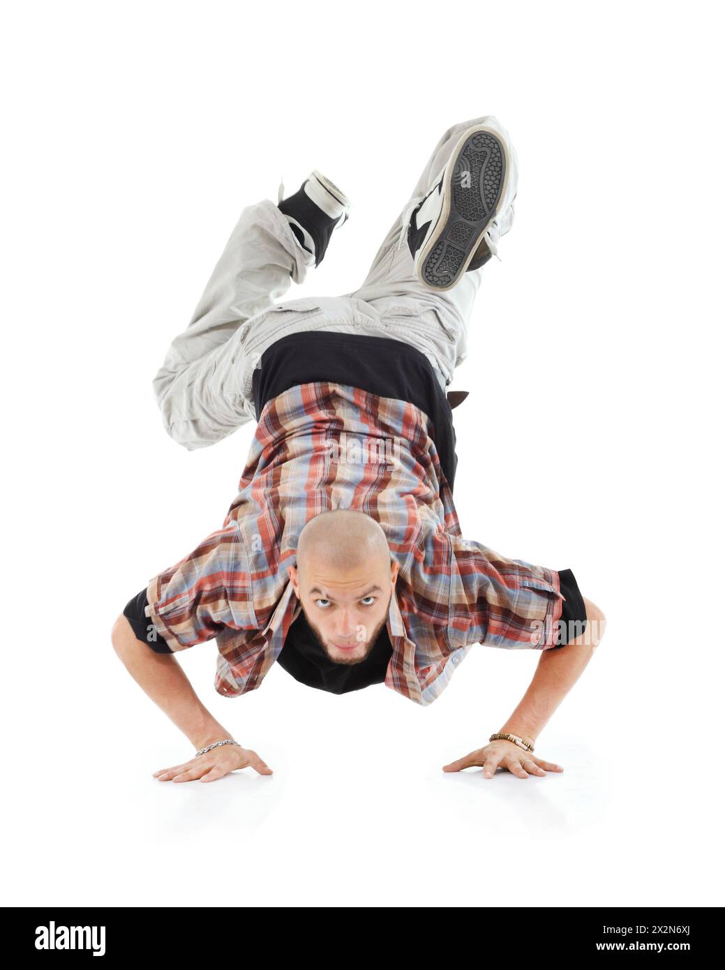 Breakdancer stands on hands and looks at camera isolated on white ...