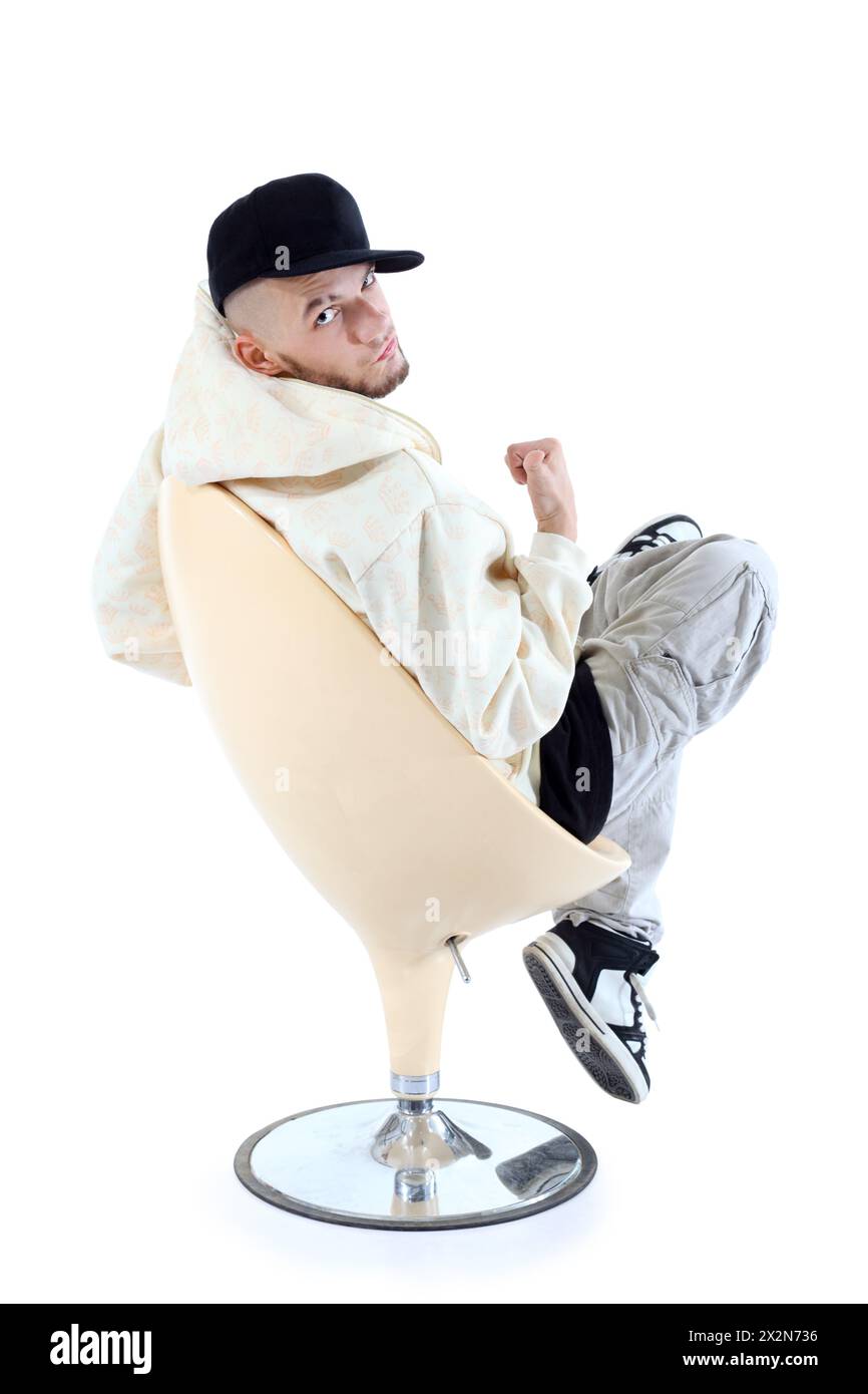 Rapper in yellow jacket sits on yellow chair with his back to camera ...