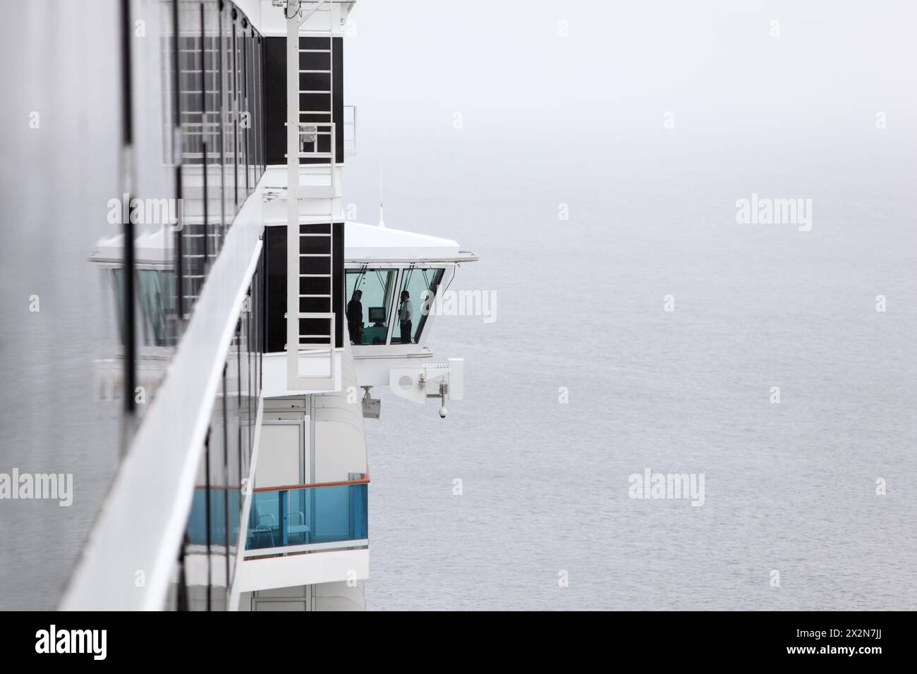 Captain stands in small booth on board of big ship and talks with ...