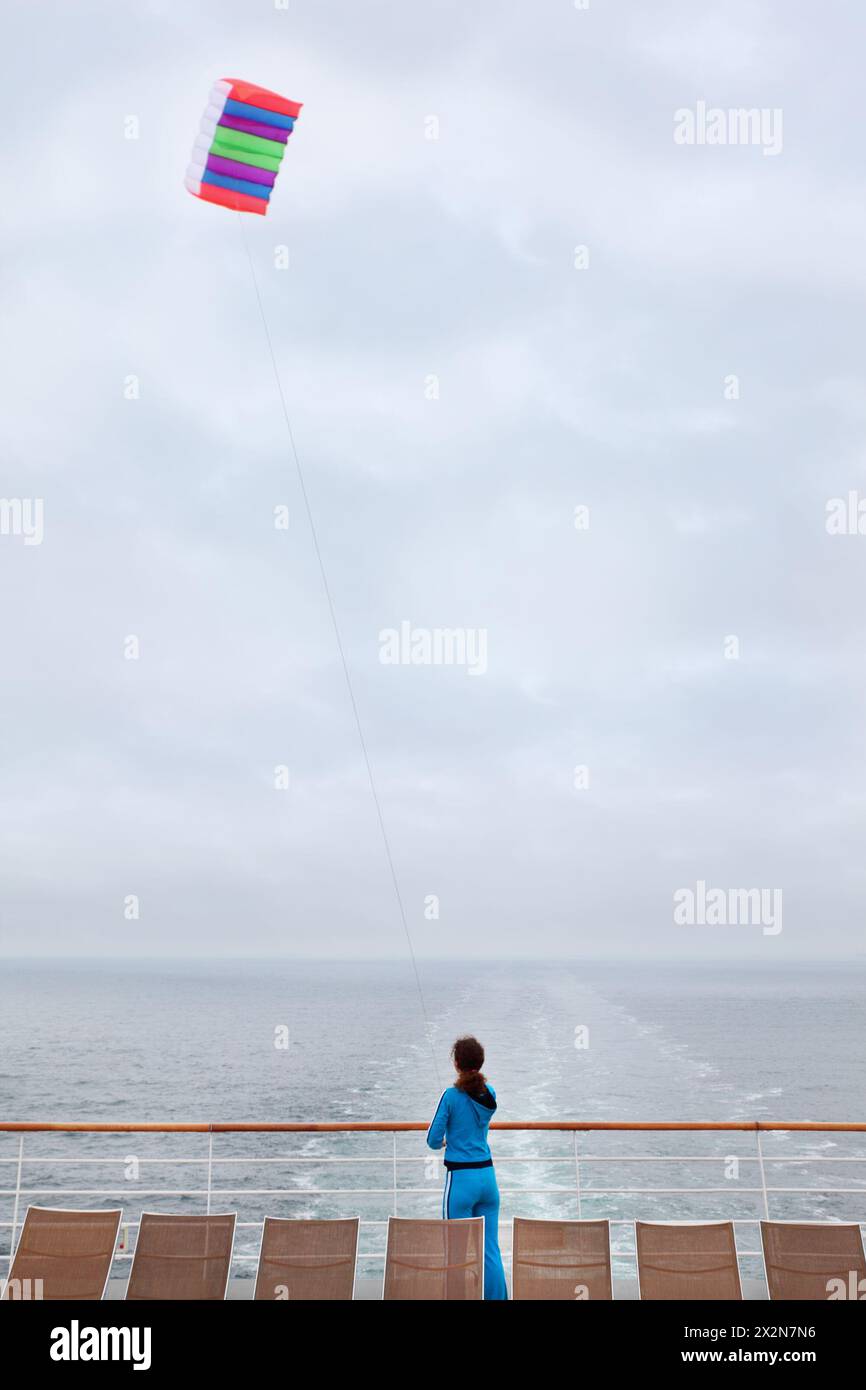 back of woman, which stands on cruise liner deck and flies kite Stock ...