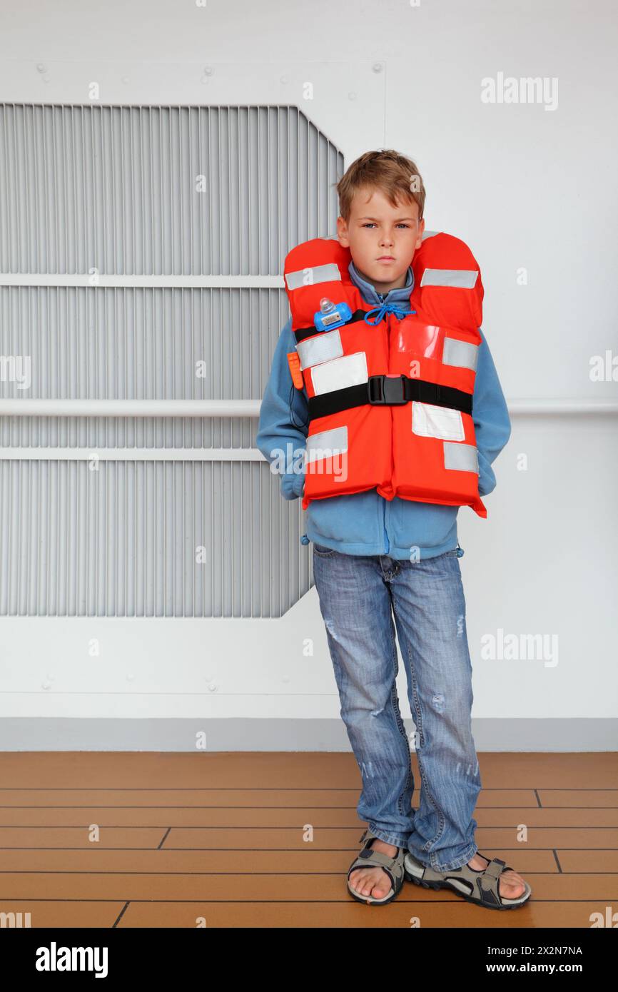 Serious boy wearing in orange life jacket stands at deck of ship Stock ...