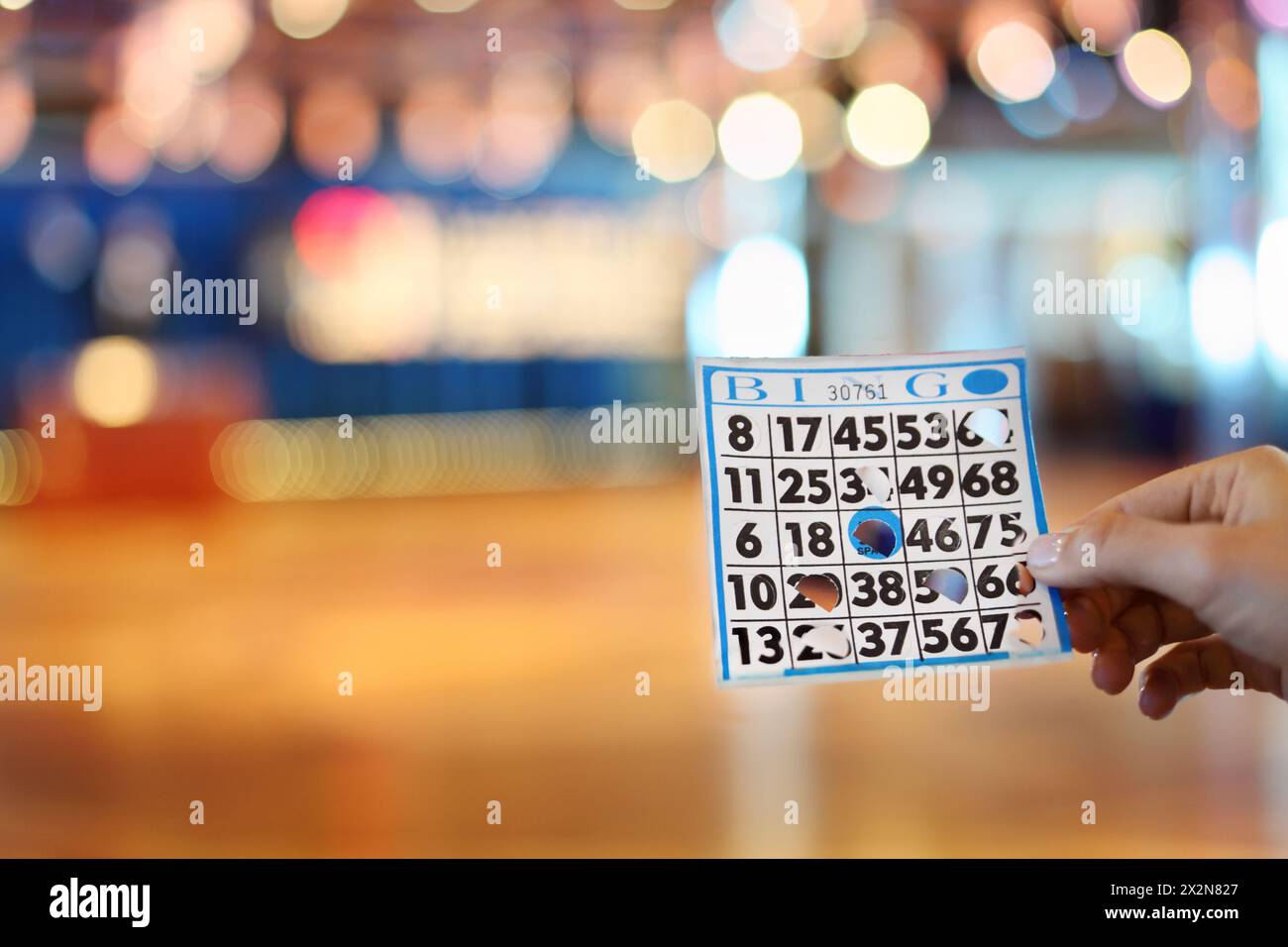 Woman hand holds bingo card with holes at background of big board Bingo ...