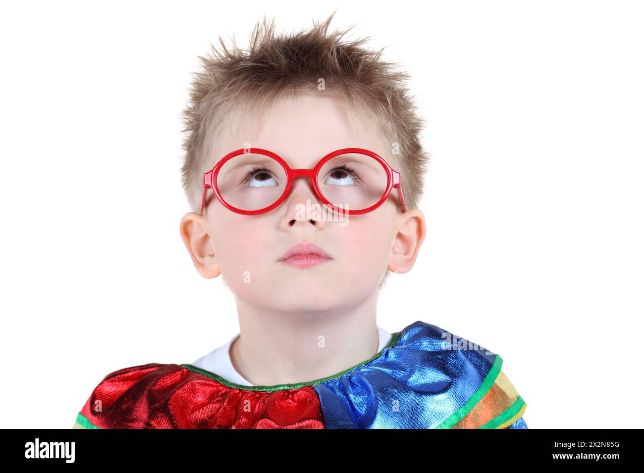 Little boy in big red glasses and clown costume looks up isolated on ...