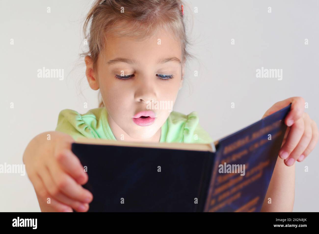Little blue eyes girl with lighting on face read blue book Stock Photo ...