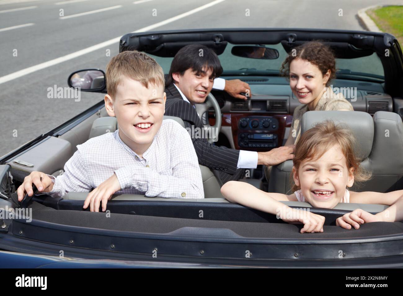 Family of four - parents and two children - sits in a cabriolet ...