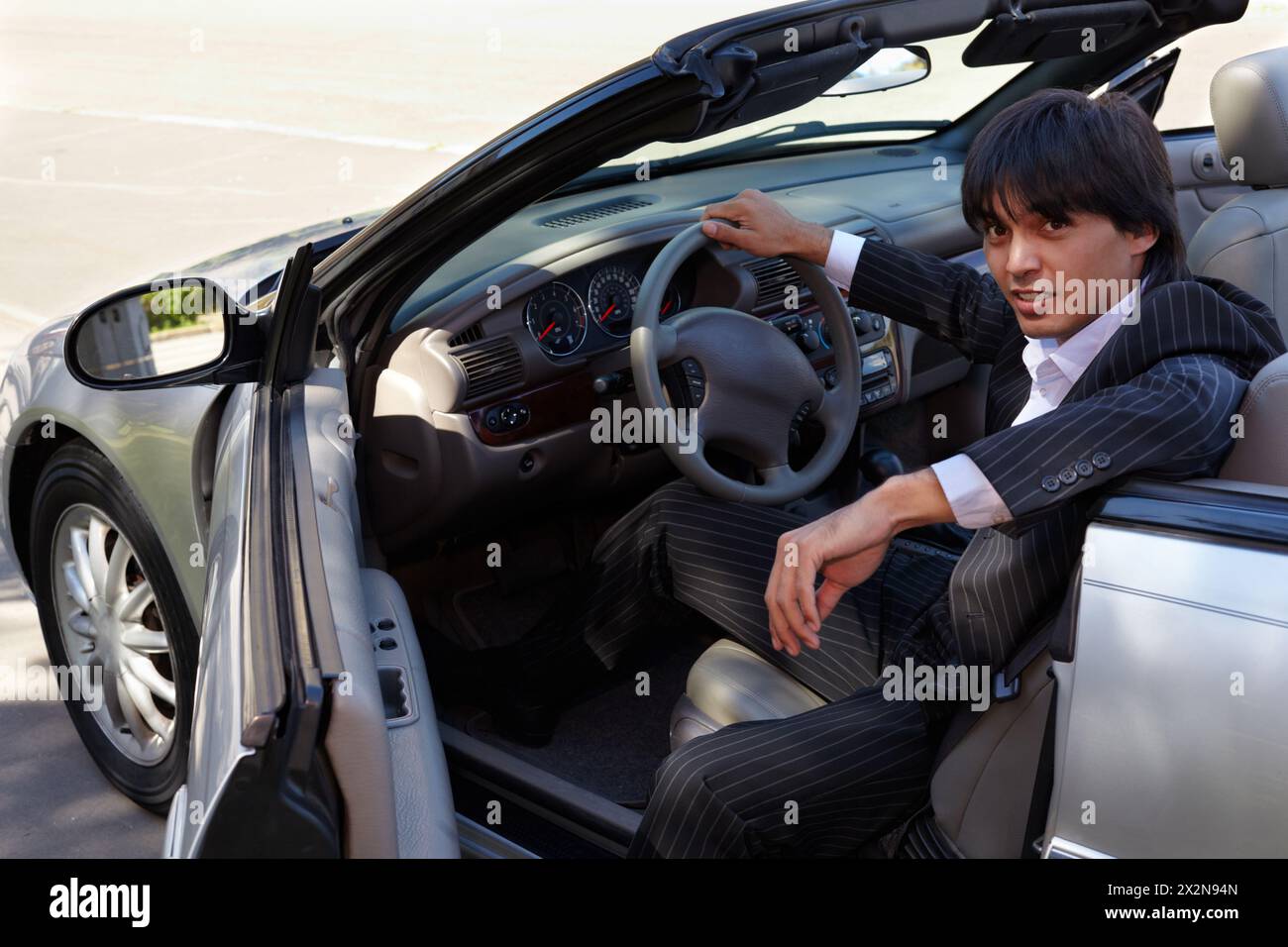 Man in a striped suit sits on a driver seat in a open top car Stock ...
