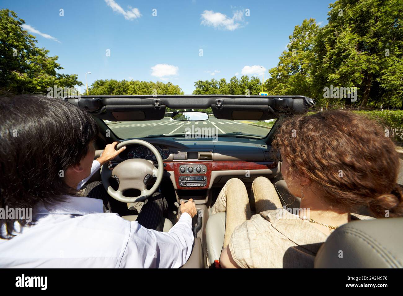 Man and woman ride in a convertible along asphalt road, back view Stock ...