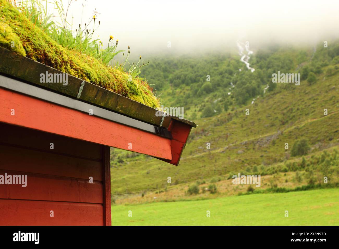 Corner of wooden roof of Norwegian house on hill, forest at valley ...