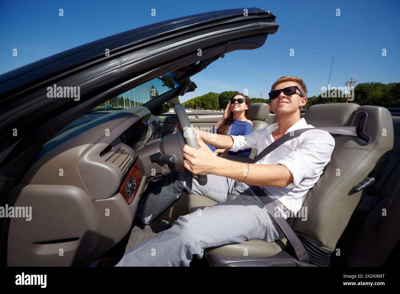 Young couple in dark sunglasses looks at the sun, sitting fastened with ...