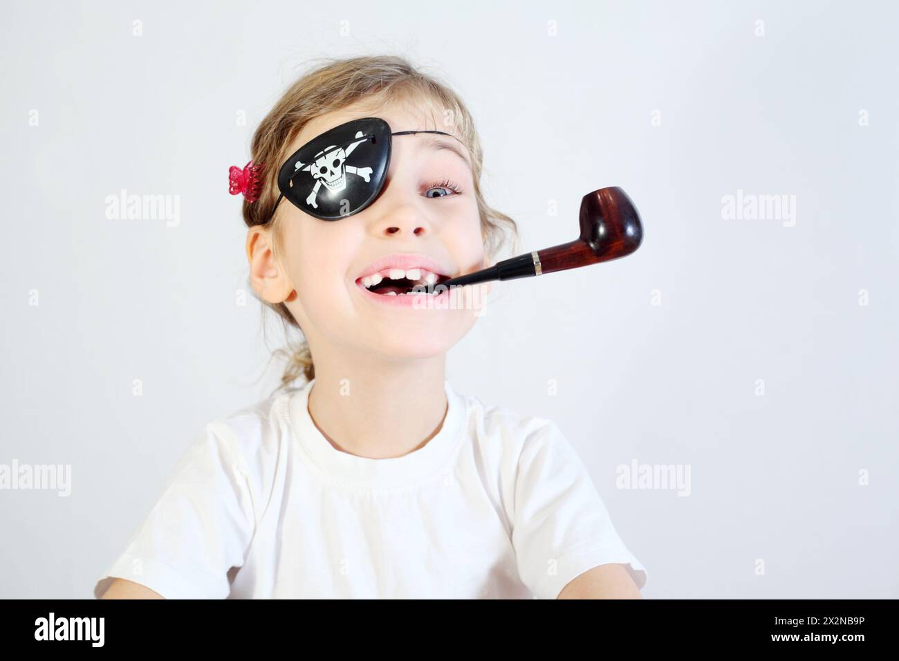 Little happy girl in white with pipeful and bandaged eye is pirate ...