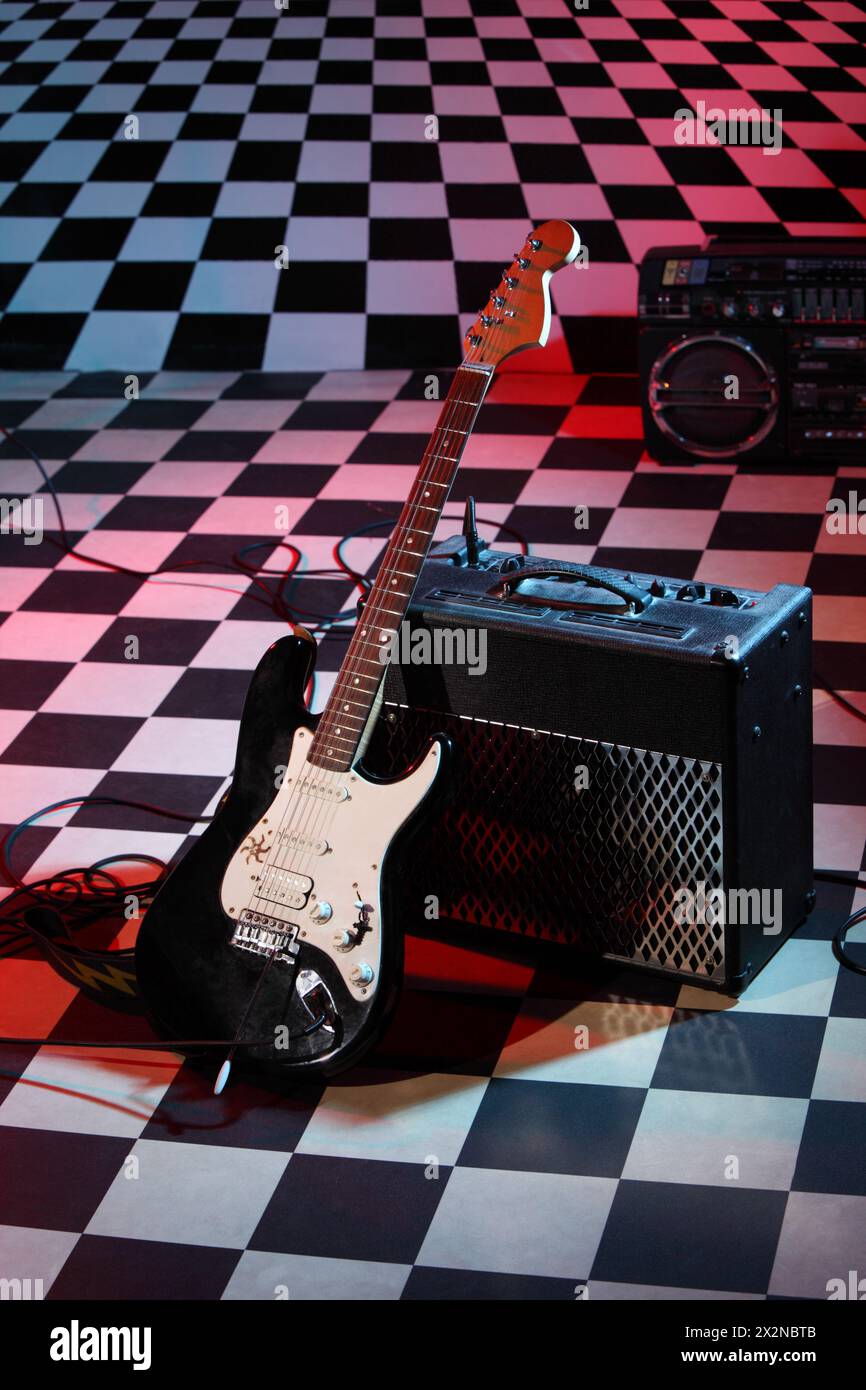 Guitar and sound amplifying equipment on checkerboard background with ...