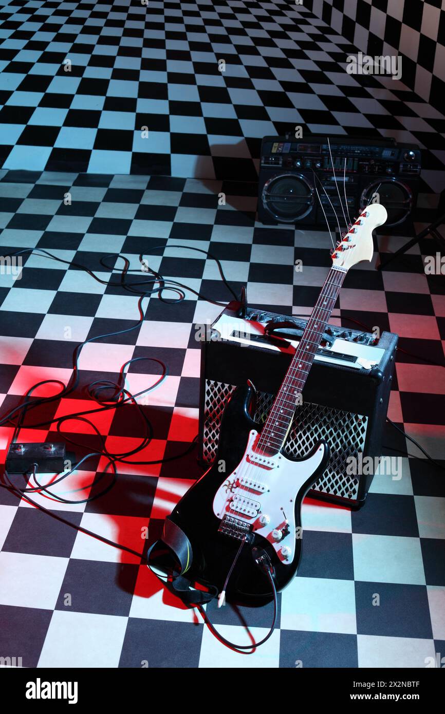 Guitar and sound amplifying equipment in studio on checkerboard ...
