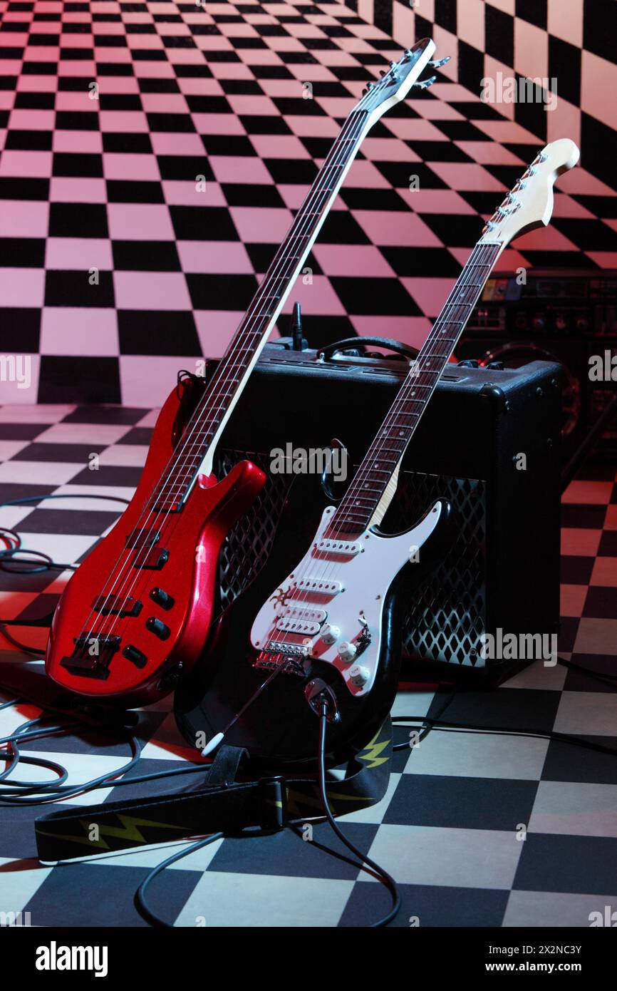 Two electric guitars and sound amplifying equipment on checkerboard ...