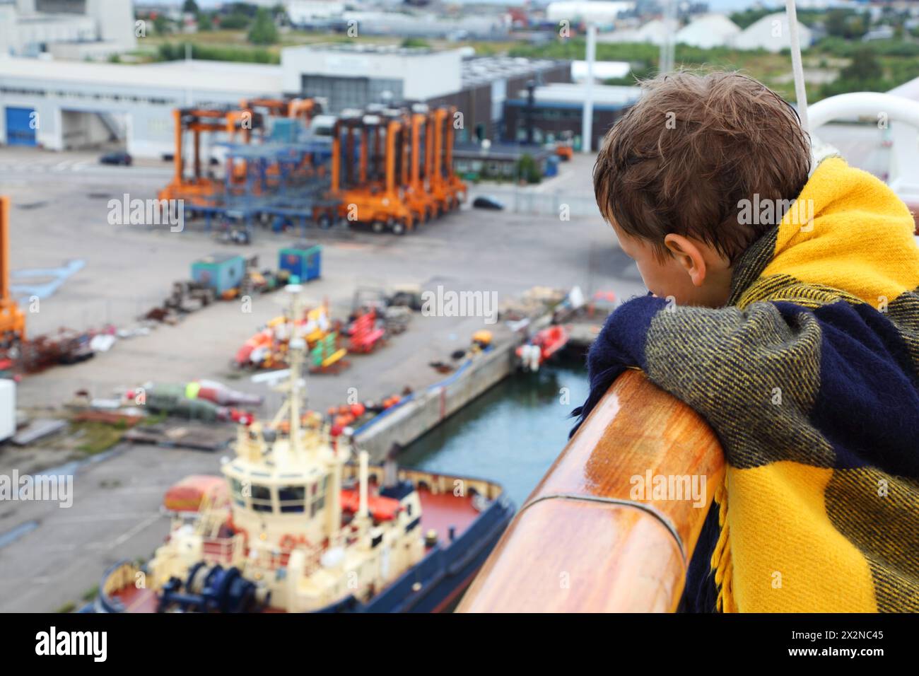 Boy wearing in plaid look at loaders, ship and buildings in port Stock ...