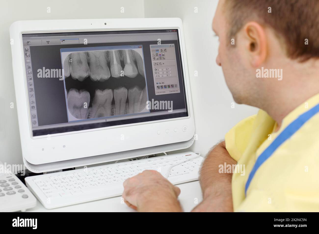 Dentist carefully looks at teeth X-rays at computer monitor in dental ...