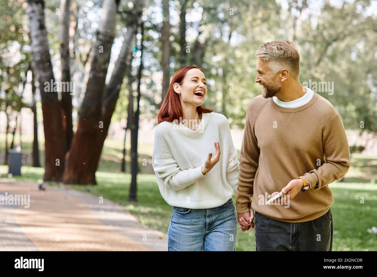A loving couple, dressed casually, walk together down a city sidewalk ...