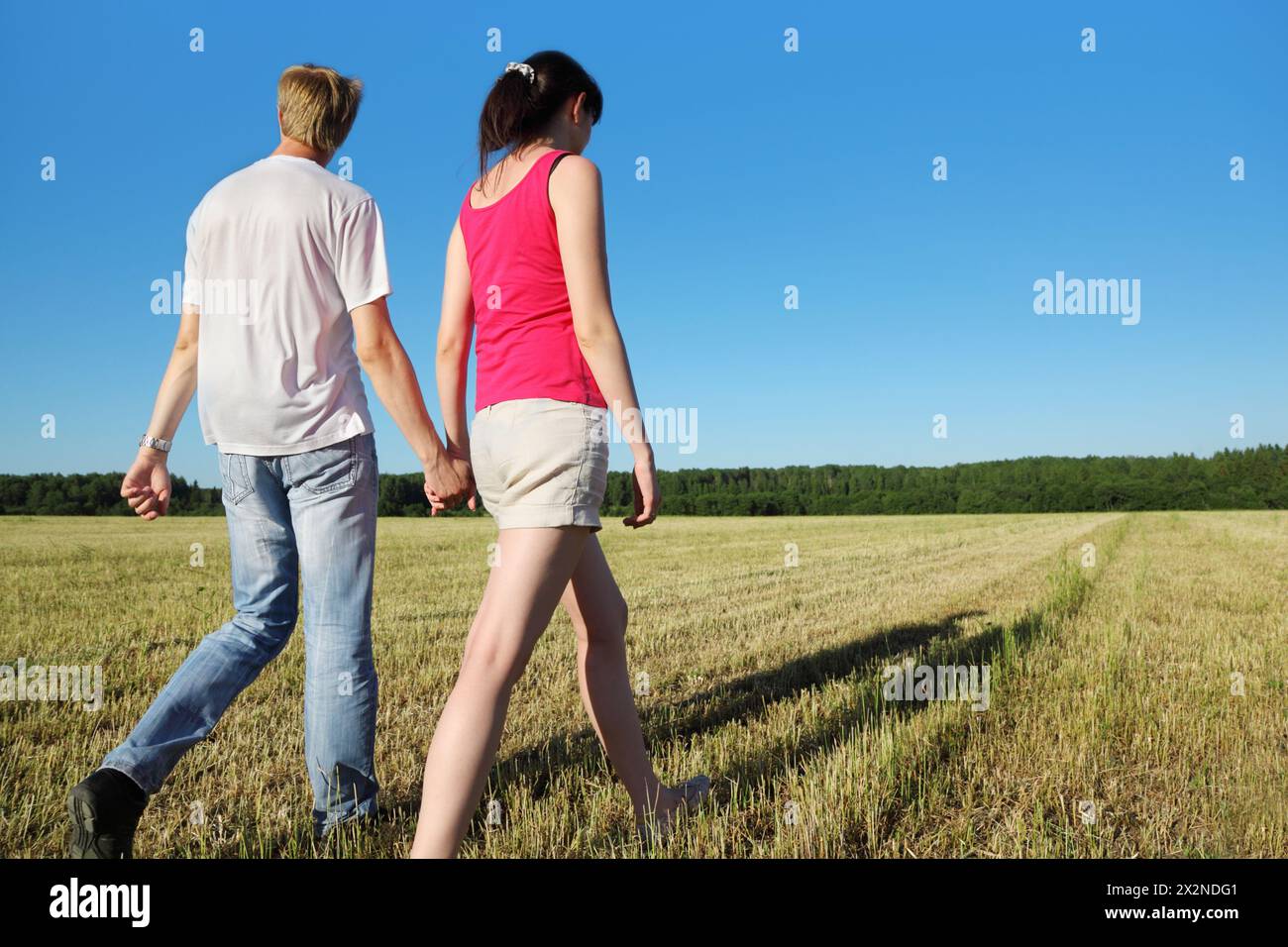 Happy husband, wife hold walk in field near wood, side Stock Photo - Alamy