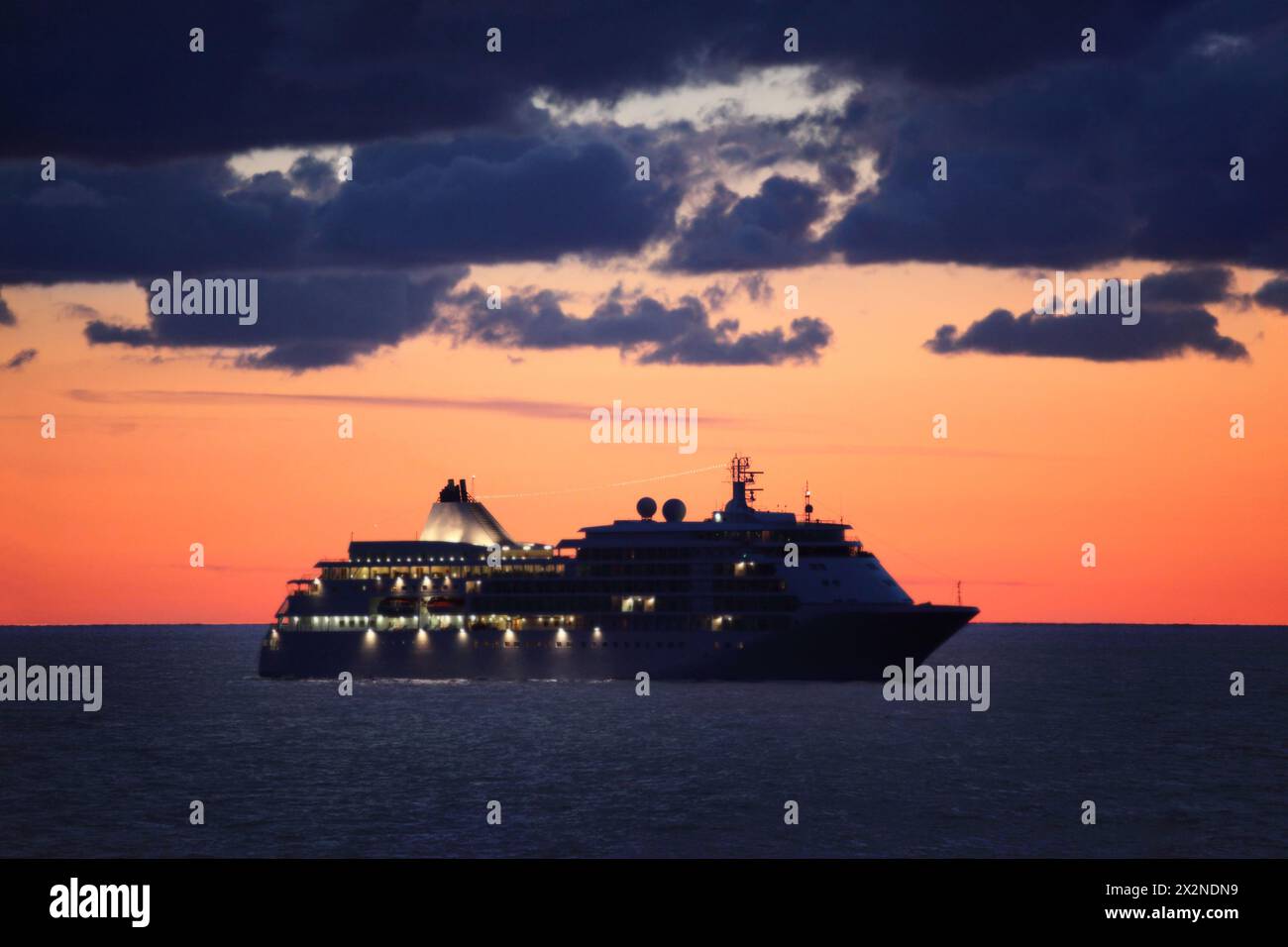 white big cruise ship silhouette in dark sea at sunset sky with clouds Stock Photo - Alamy