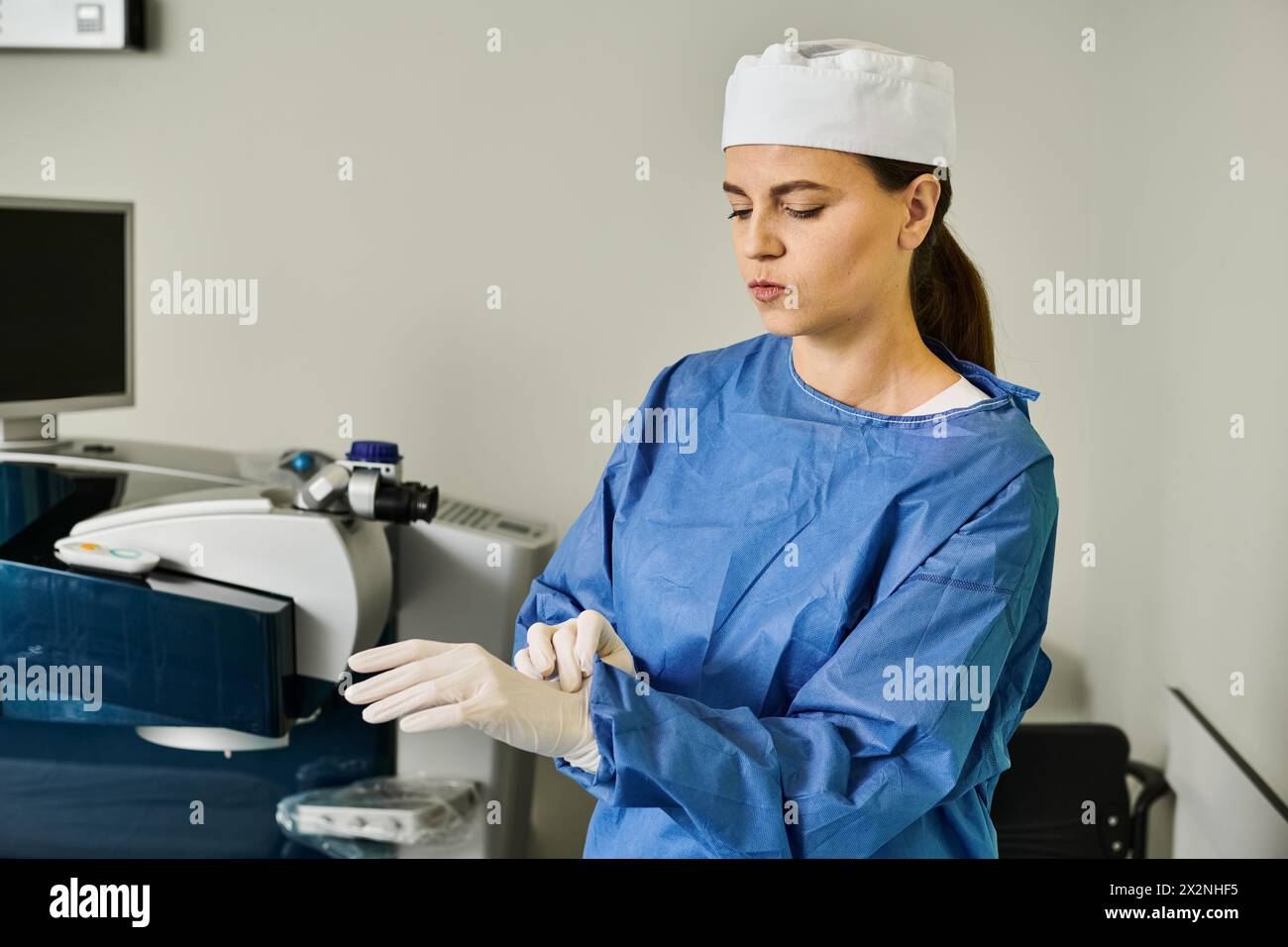 A woman in scrubs studies a computer screen in a clinic Stock Photo - Alamy