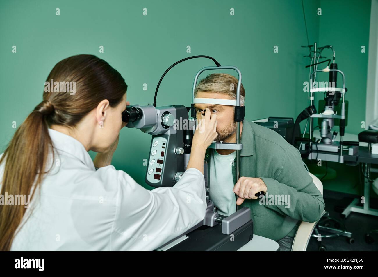Woman examines mans eyes through a microscope in a doctors office for ...
