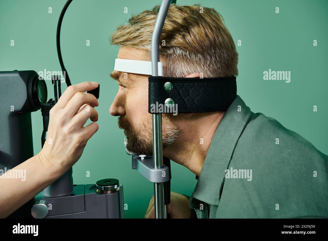 Dedicated doctor examines mans eyes through a microscope in a doctors ...