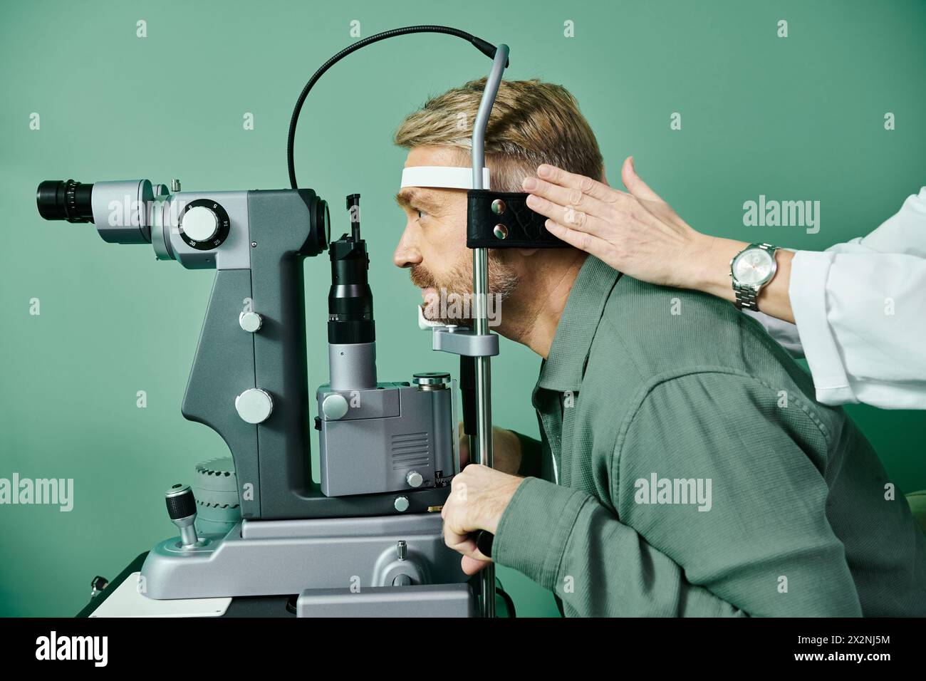 Hard working doctor examines mans eyes through a microscope in a ...