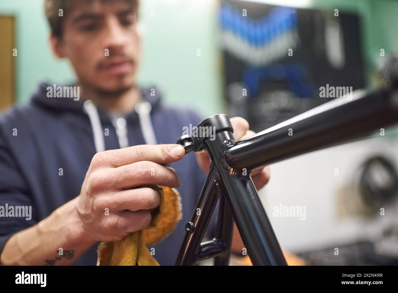 Young hispanic man assembling a bicycle in his bike shop as part of a ...