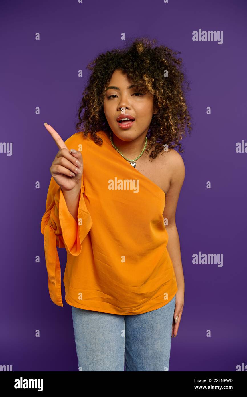 Beautiful African American woman in an orange top pointing at the ...