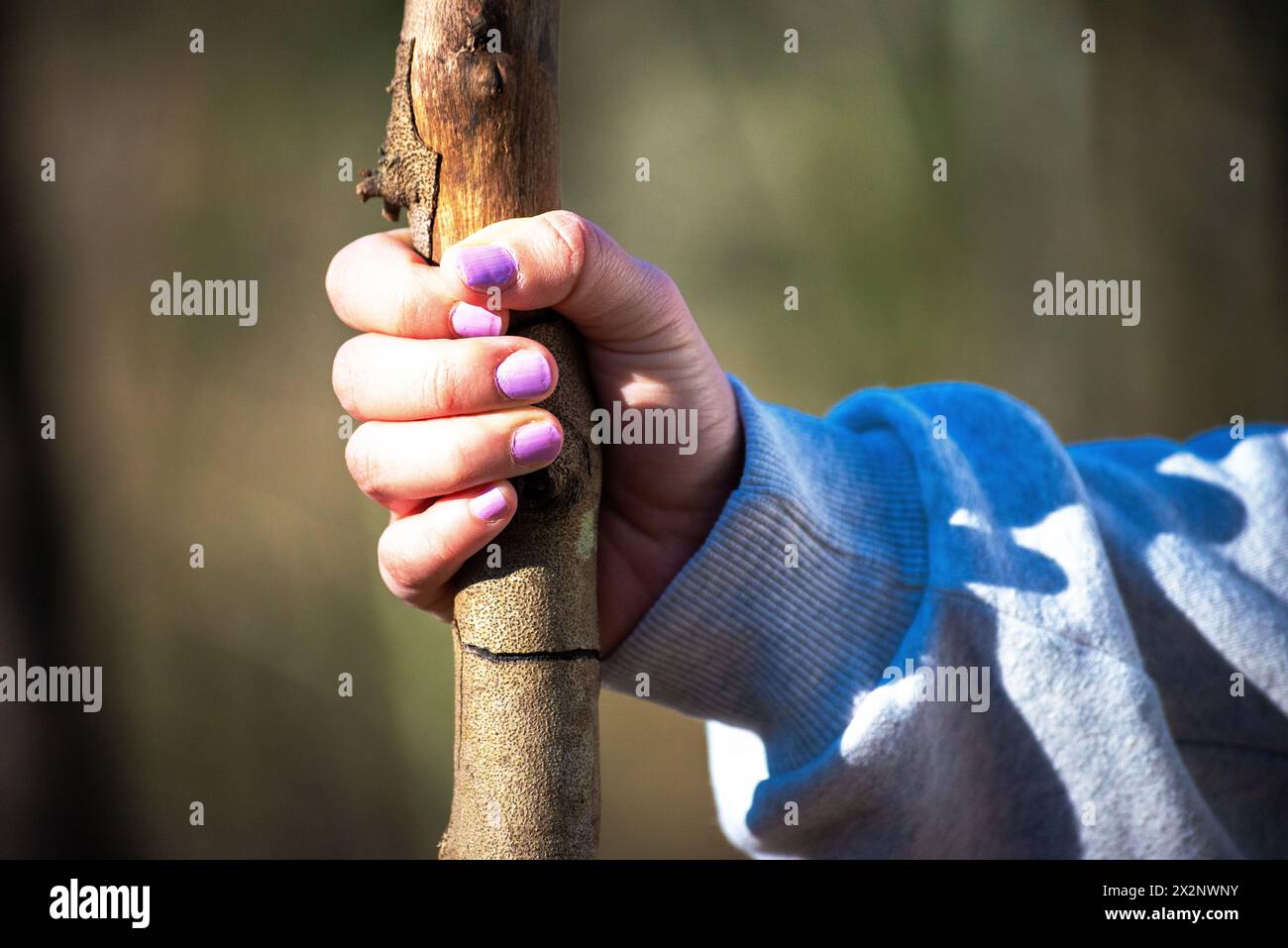 In the serene forest, a woman gracefully holds a rod stick, embodying ...