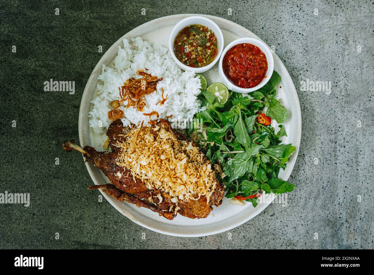 Deep fried duck with rice, green vegetables, and two types of sambals ...