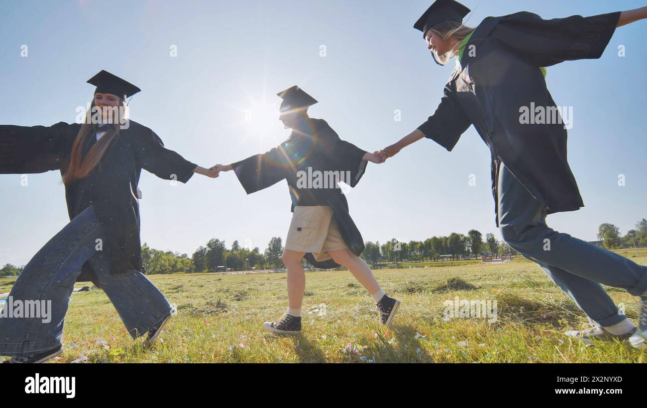 College graduates holding hands run in a round dance Stock Photo - Alamy