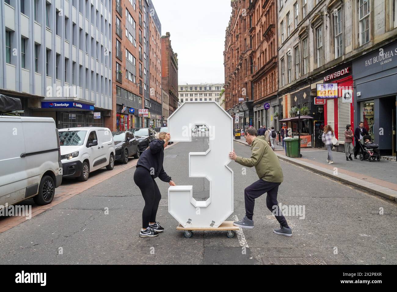 Shop workers moving the oversized number three, 3, across Queen Street ...