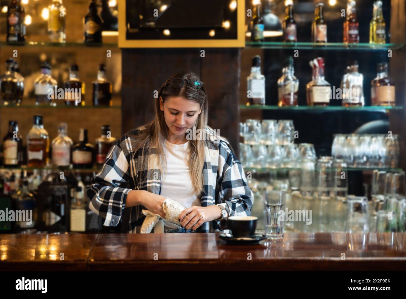 Waitress standing in bar and wiping and polishing beer glass. Bartender ...