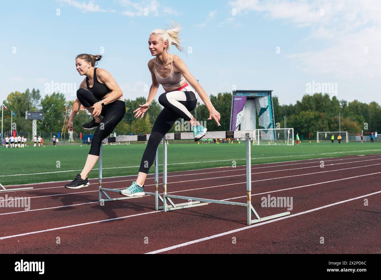 Two athlete woman runnner running hurdles at the stadium outdoors Stock ...